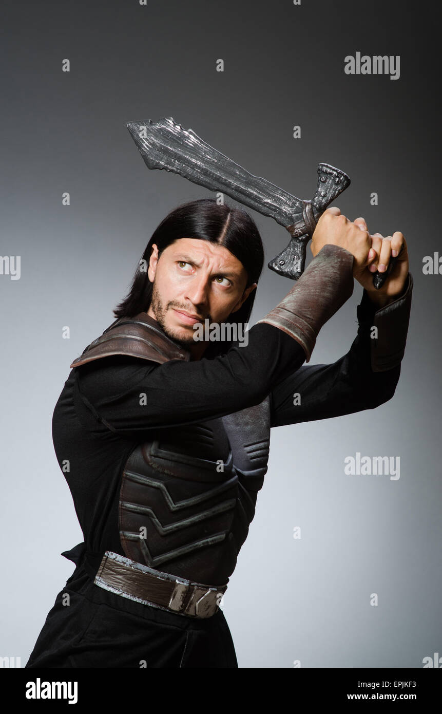 Angry knight with sword against dark background Stock Photo - Alamy