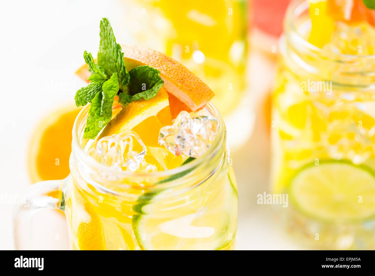 Infused water with fresh citrus fruits and ice Stock Photo - Alamy