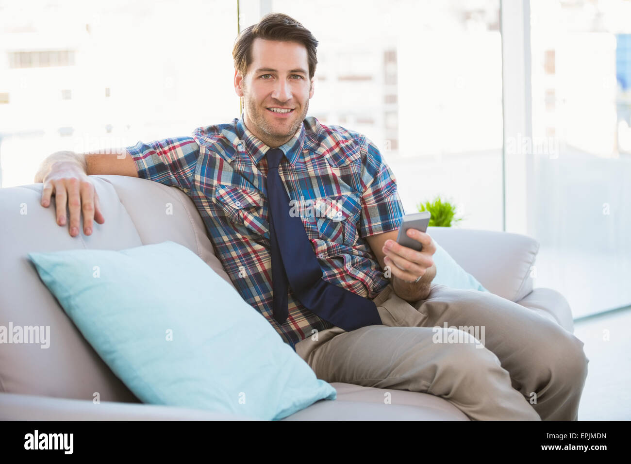 Happy man sitting on the couch sending a text message Stock Photo - Alamy