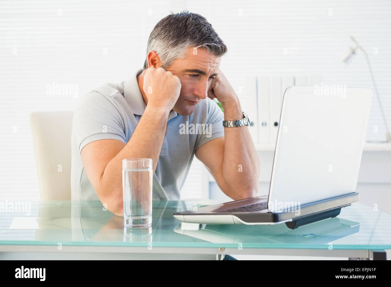 Tired man sitting and looking his laptop Stock Photo - Alamy