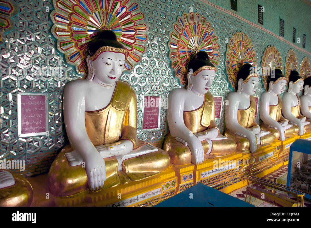 Long row of painted stone Buddhas against a green temple wall in the ...