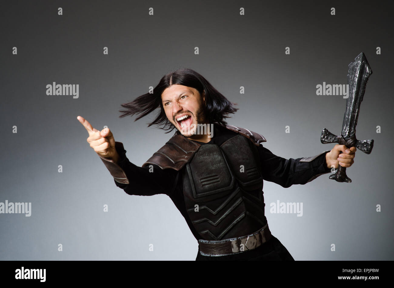 Angry knight with sword against dark background Stock Photo - Alamy