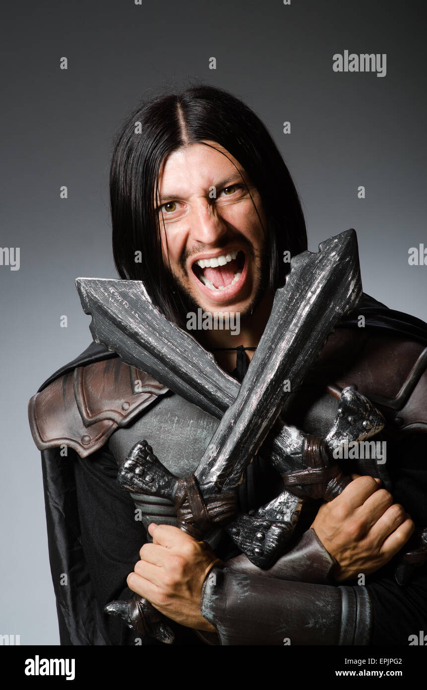 Angry knight with sword against dark background Stock Photo - Alamy