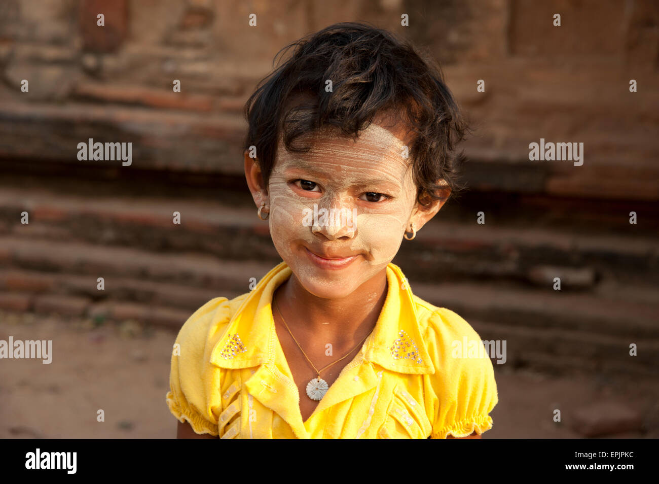 Portrait of a small Burmese girl wearing yellow top with sandalwood ...