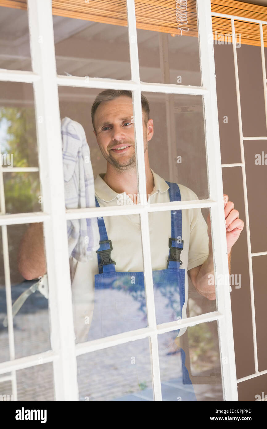 Handyman cleaning the window and smiling Stock Photo - Alamy