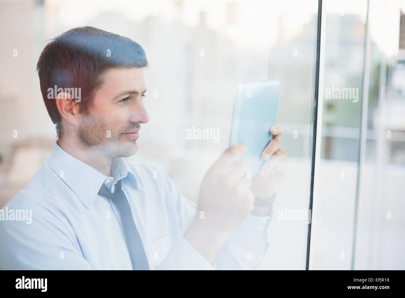 Businessman using tablet seen through window Stock Photo - Alamy