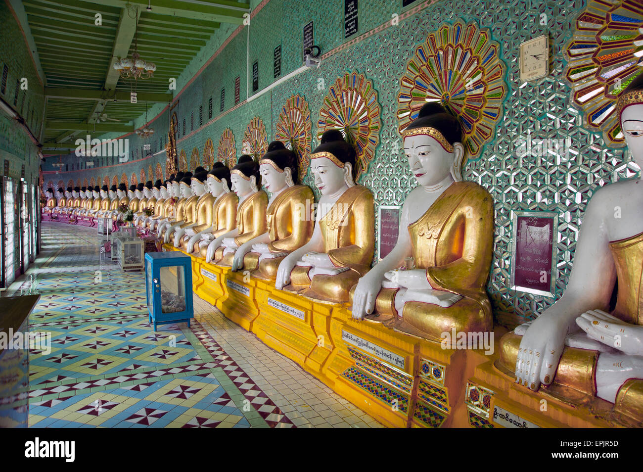 Long row of painted stone Buddhas against a green temple wall in the ...