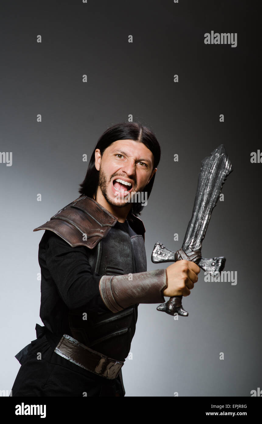 Angry knight with sword against dark background Stock Photo - Alamy
