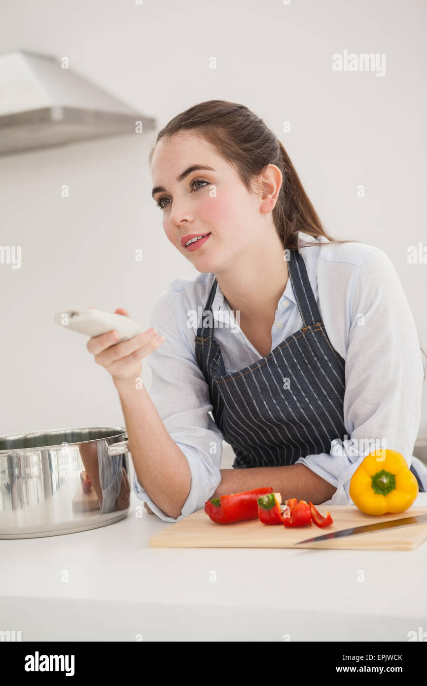 Pretty brunette cooking and watching tv Stock Photo - Alamy