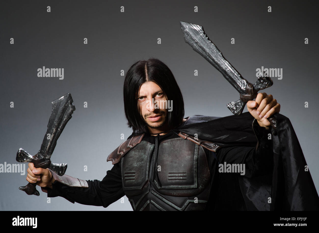Angry knight with sword against dark background Stock Photo - Alamy