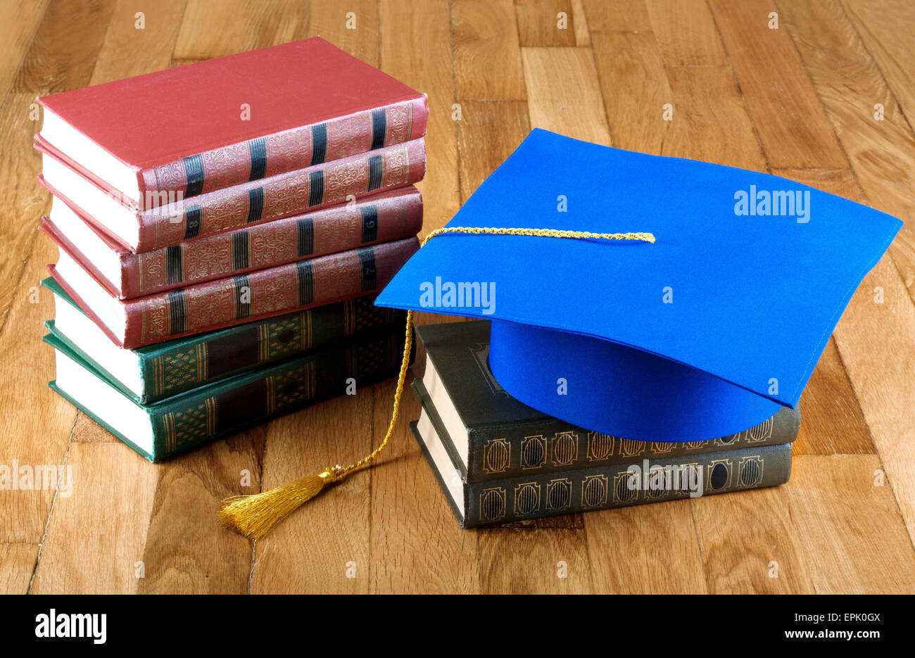 Graduation mortarboard on top of stack of books on wooden background of ...
