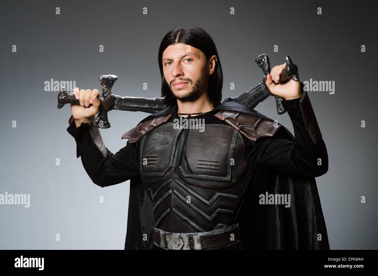 Angry knight with sword against dark background Stock Photo - Alamy