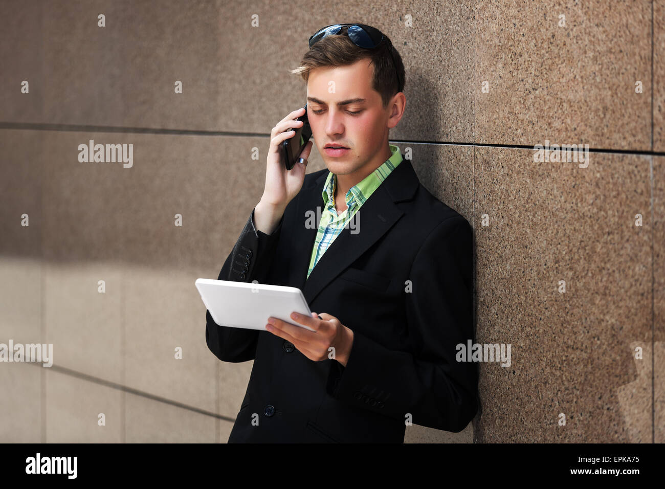 Young man with tablet computer calling on phone Stock Photo - Alamy