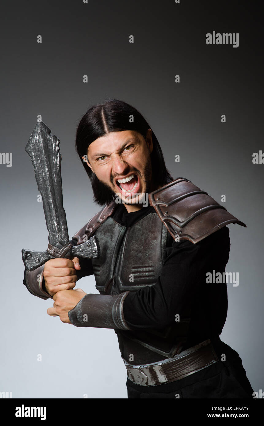 Angry knight with sword against dark background Stock Photo - Alamy