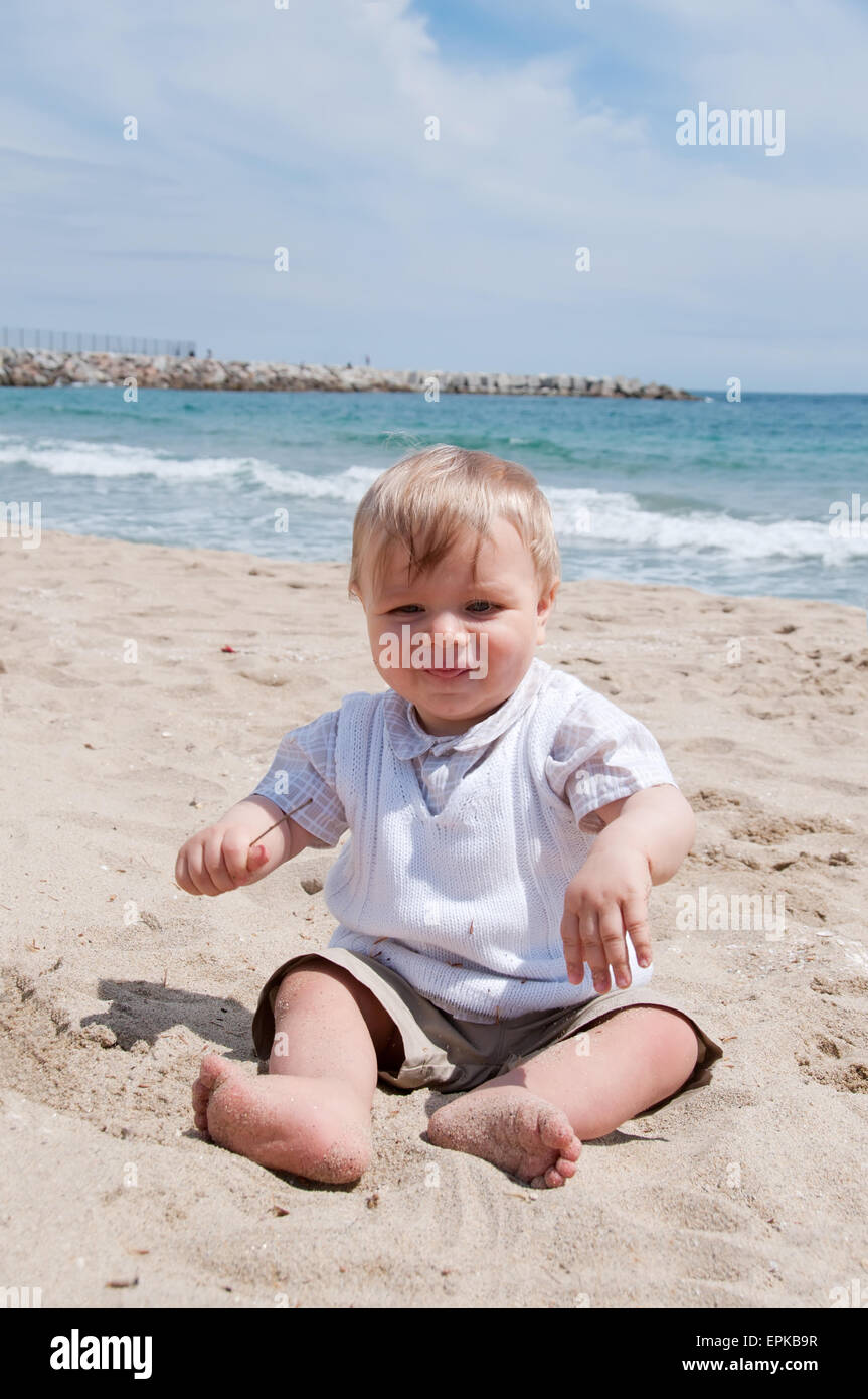 Happy boy sitting on the beach Stock Photo - Alamy