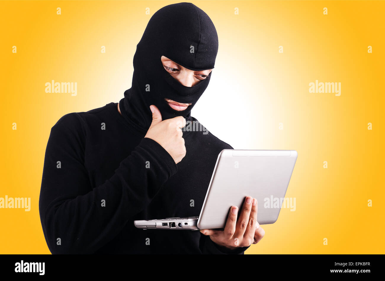 Hacker with computer wearing balaclava Stock Photo - Alamy