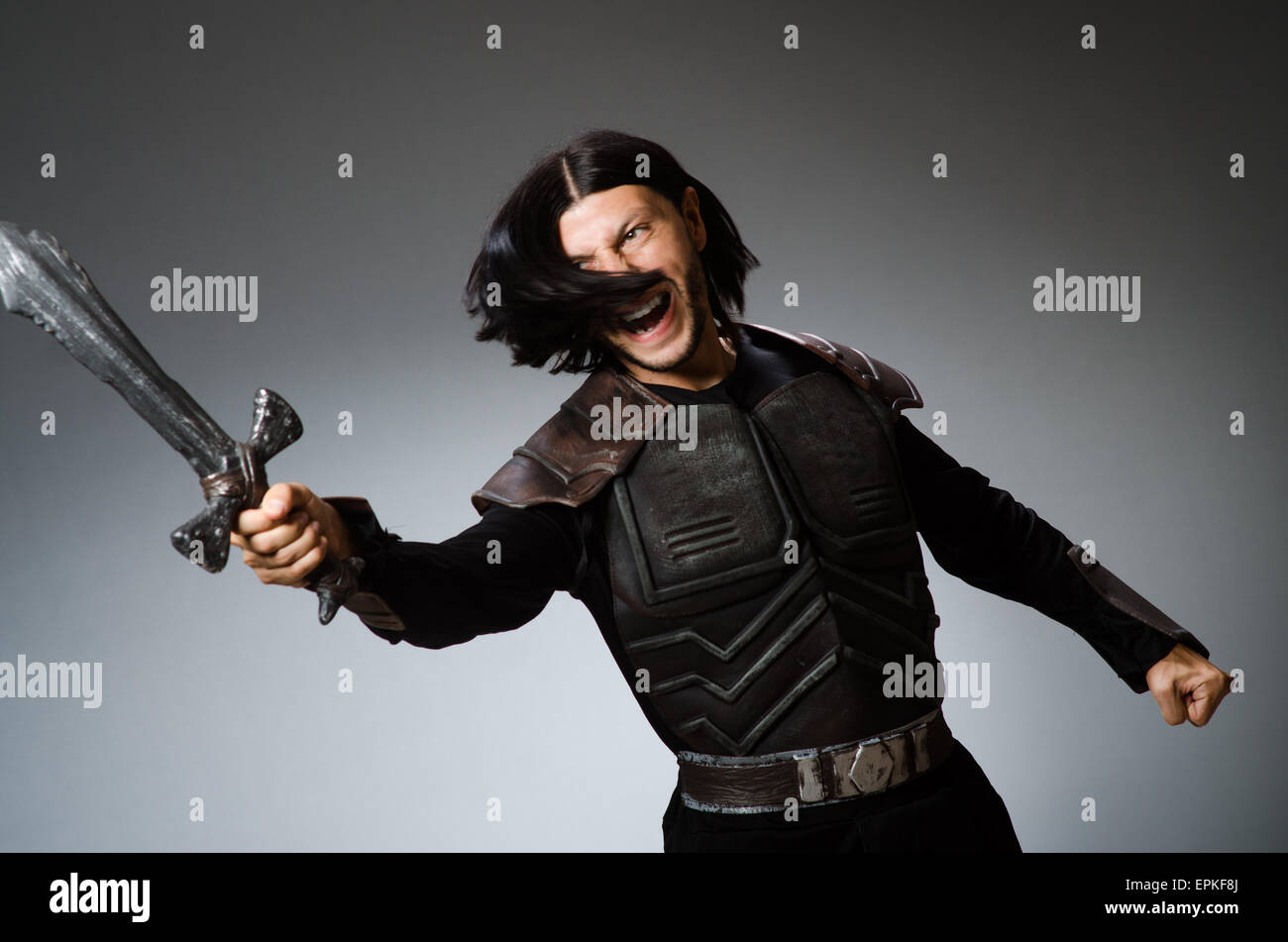Angry knight with sword against dark background Stock Photo - Alamy
