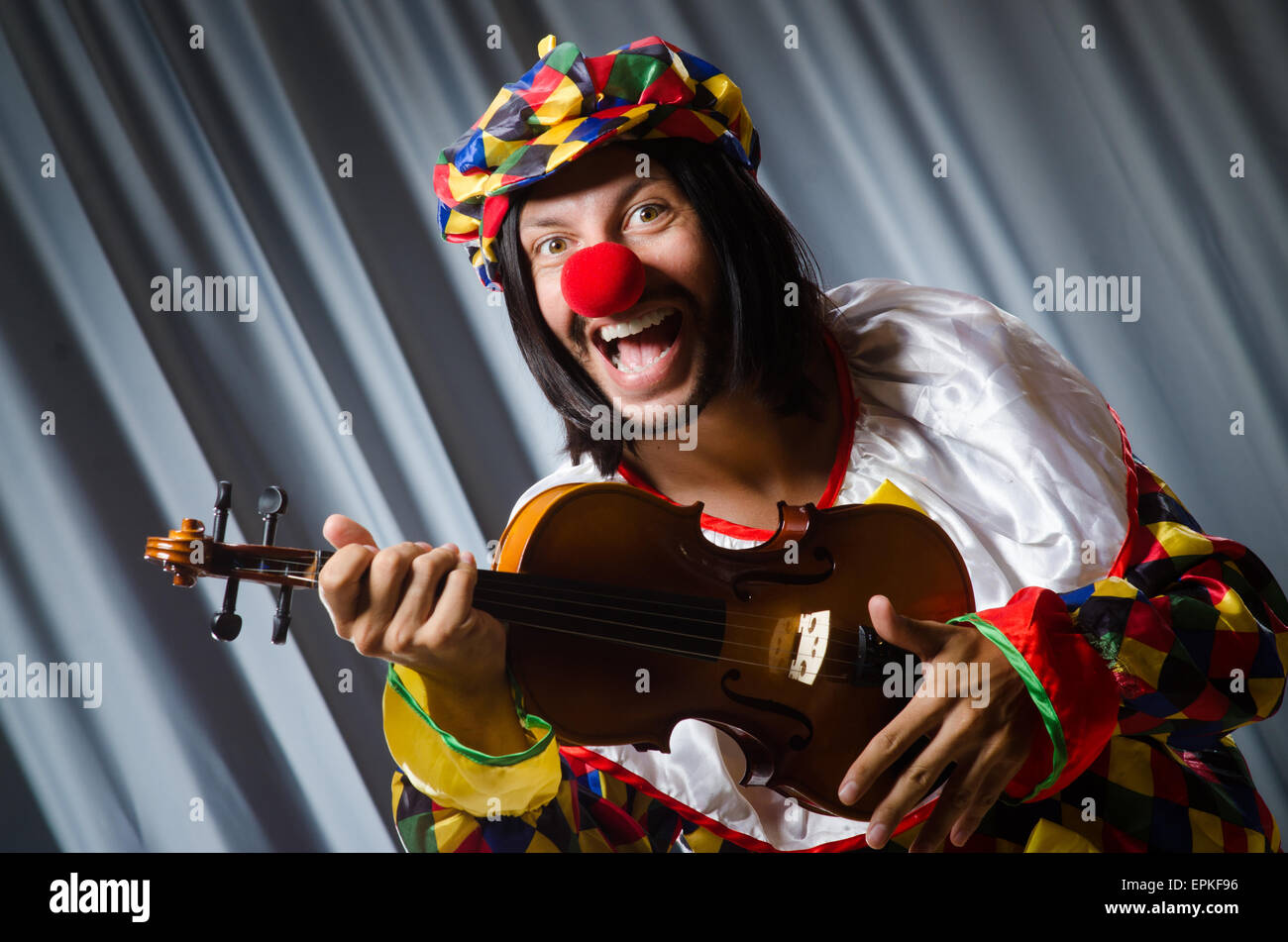 Funny clown plyaing violin against curtain Stock Photo - Alamy