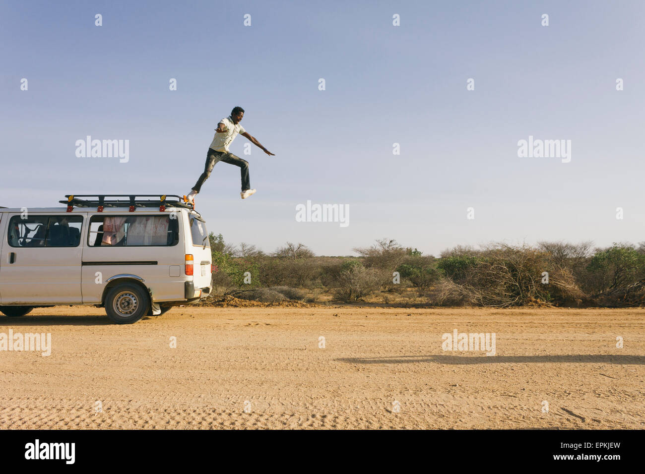 Ethiopia, man jumping from the roof of a van on a dirt road in african ...