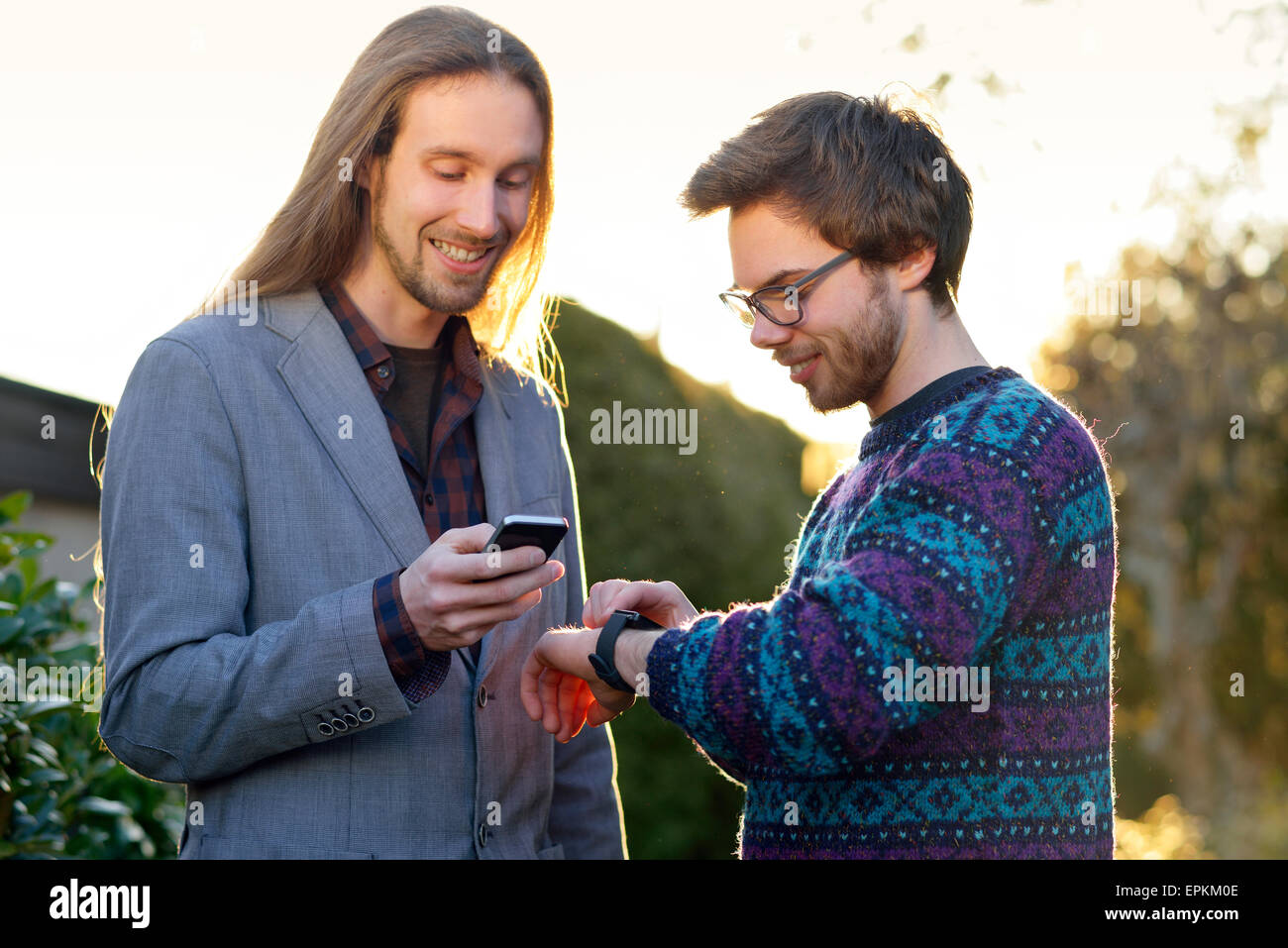 Two hipsters with smartwatch and smartphone Stock Photo - Alamy