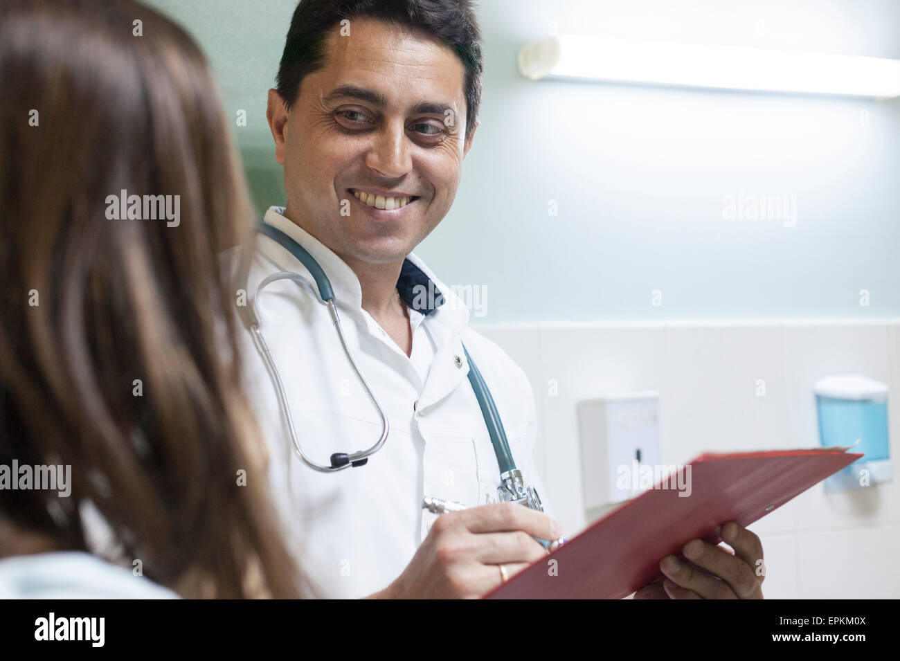 Smiling doctor taking notes while listening to patient Stock Photo - Alamy