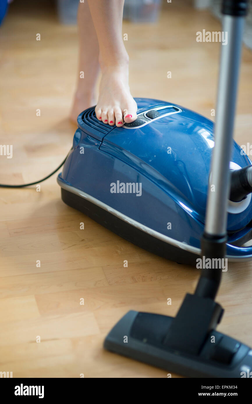 Woman's foot switching on vacuum cleaner Stock Photo - Alamy