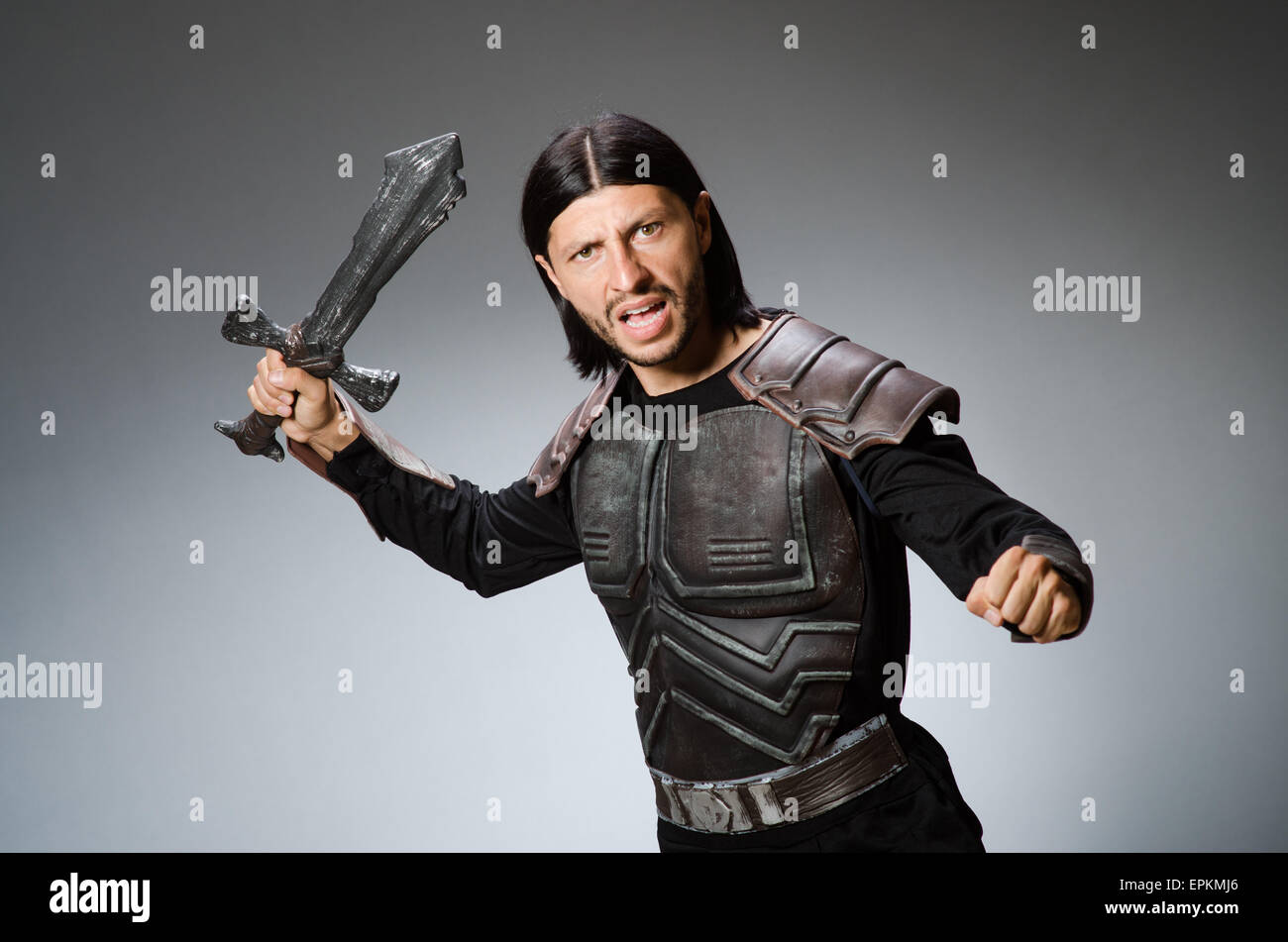 Angry knight with sword against dark background Stock Photo - Alamy