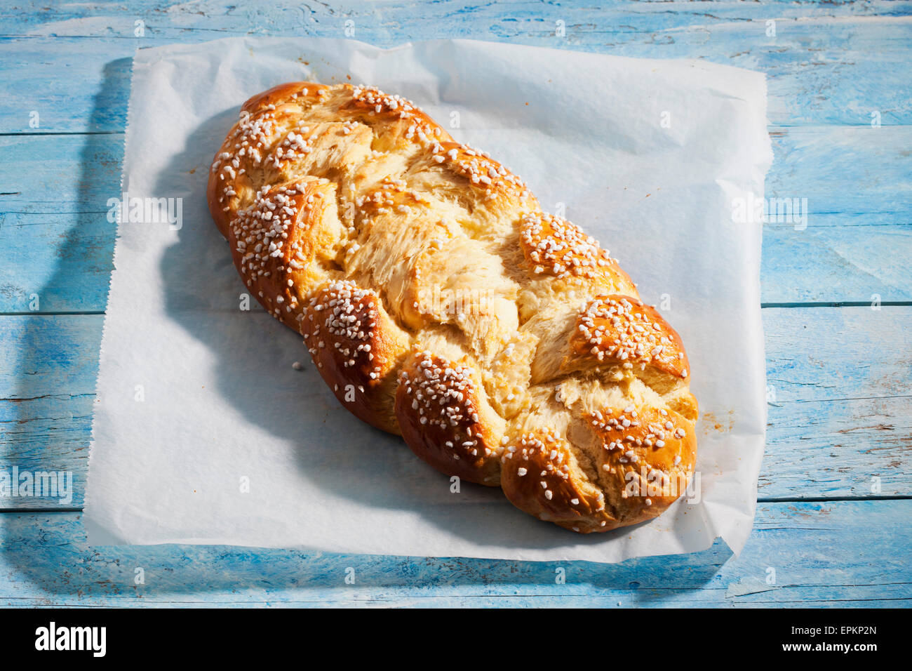 Plaited yeast bun with coarse sugar on parchment paper Stock Photo - Alamy