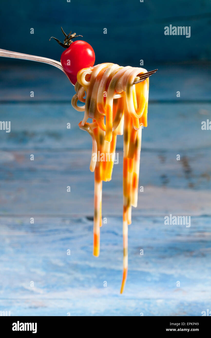 Cooked coloured Linguini and raw cherry tomato on a fork Stock Photo ...