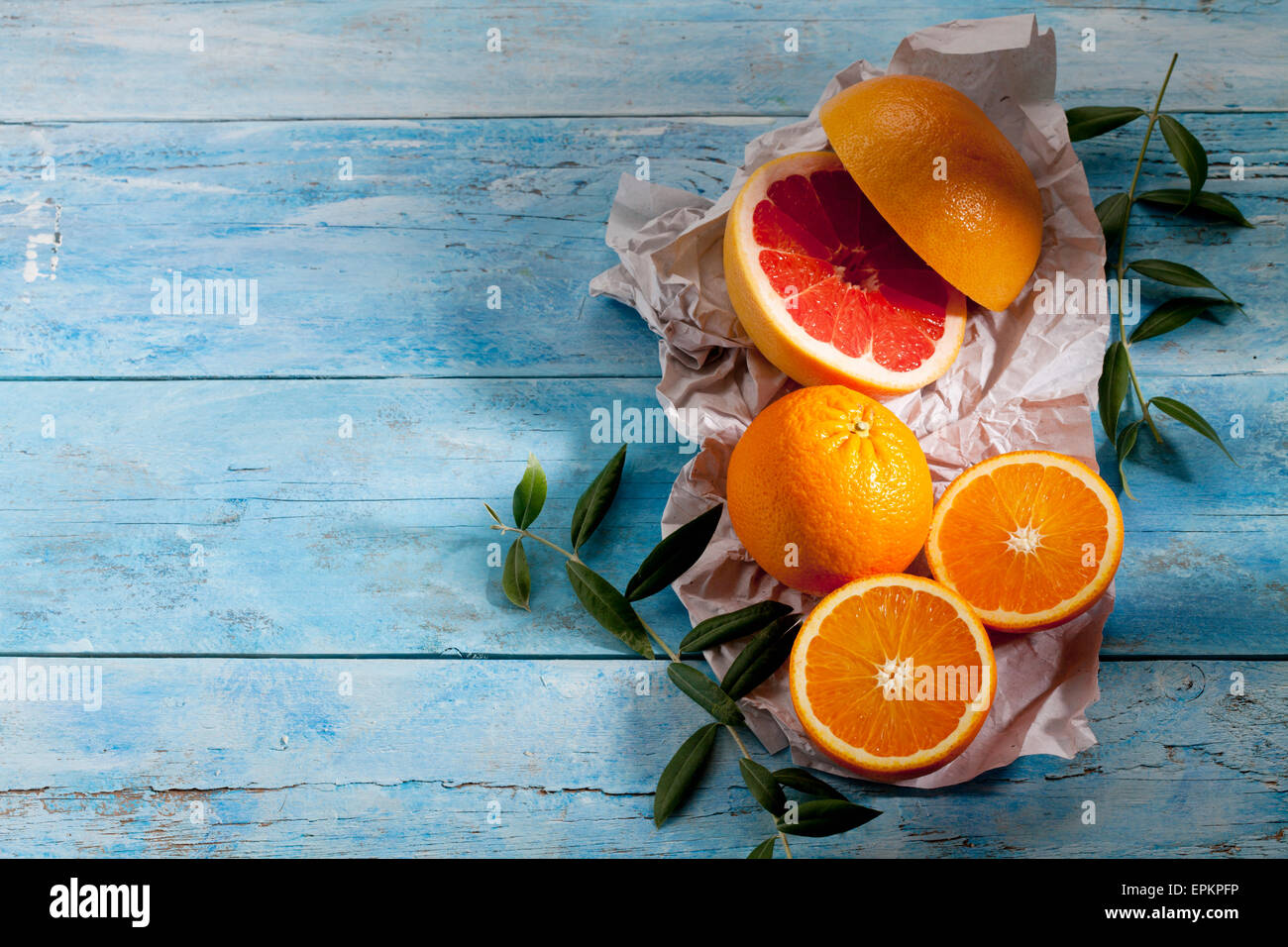 Sliced pink grapefruit, whole and sliced oranges on paper Stock Photo ...