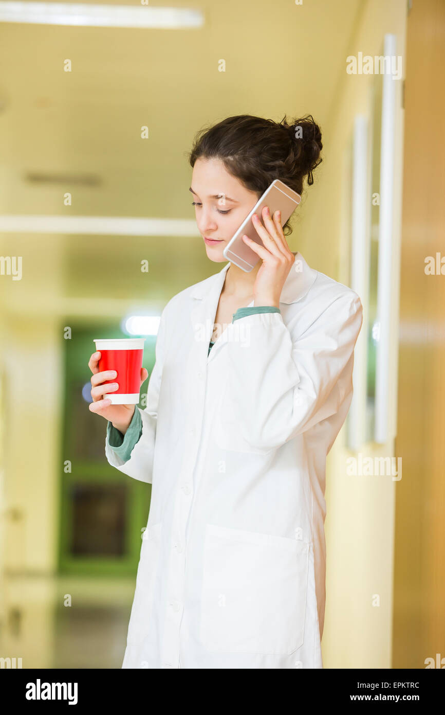 Young doctor with cell phone and coffee cup on hospital floor Stock ...