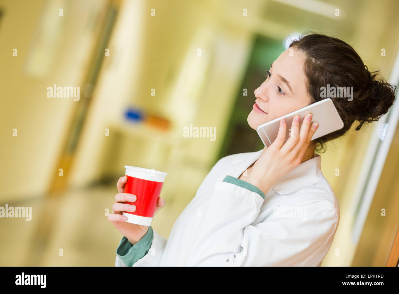 Young doctor with cell phone and coffee cup on hospital floor Stock ...