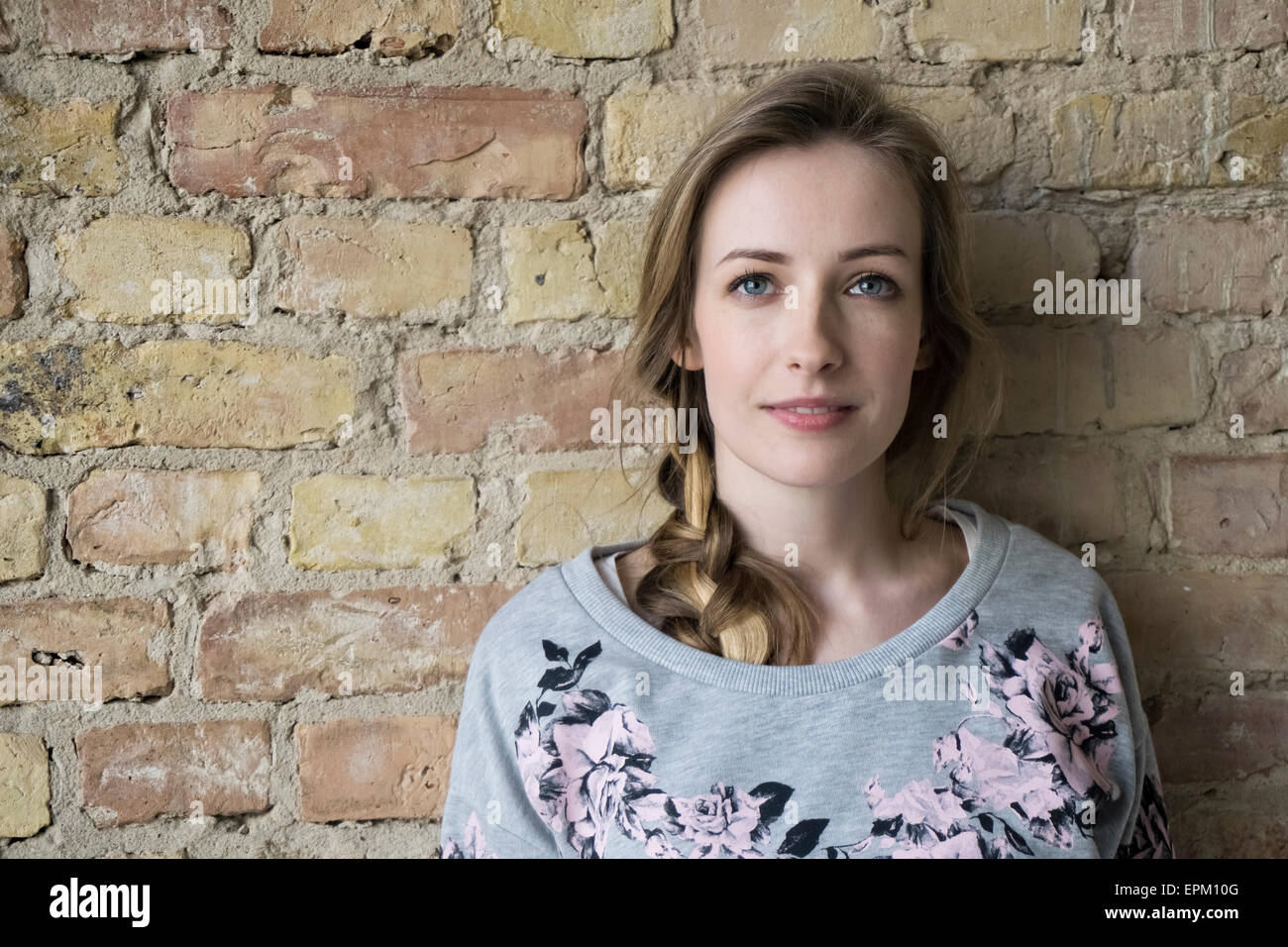 Portrait of young woman in front of brick wall Stock Photo - Alamy