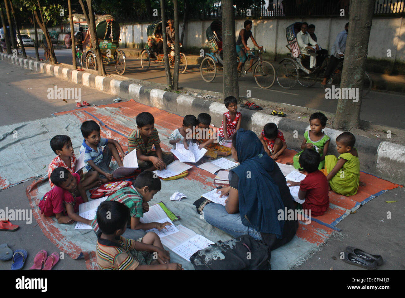 Bangladeshi street children study at the roadside at Poribug in Dhaka ...