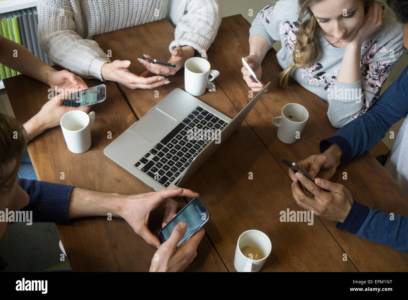 Group of friends using smartphones in a cafeteria Stock Photo - Alamy
