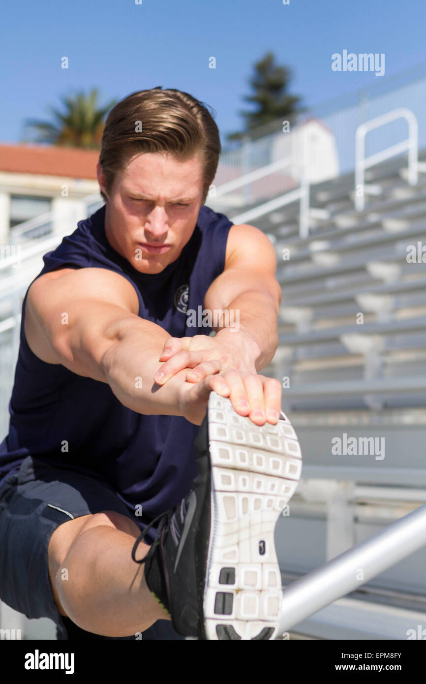 USA, California, San Luis Obispo, young man doing stretching exercises ...