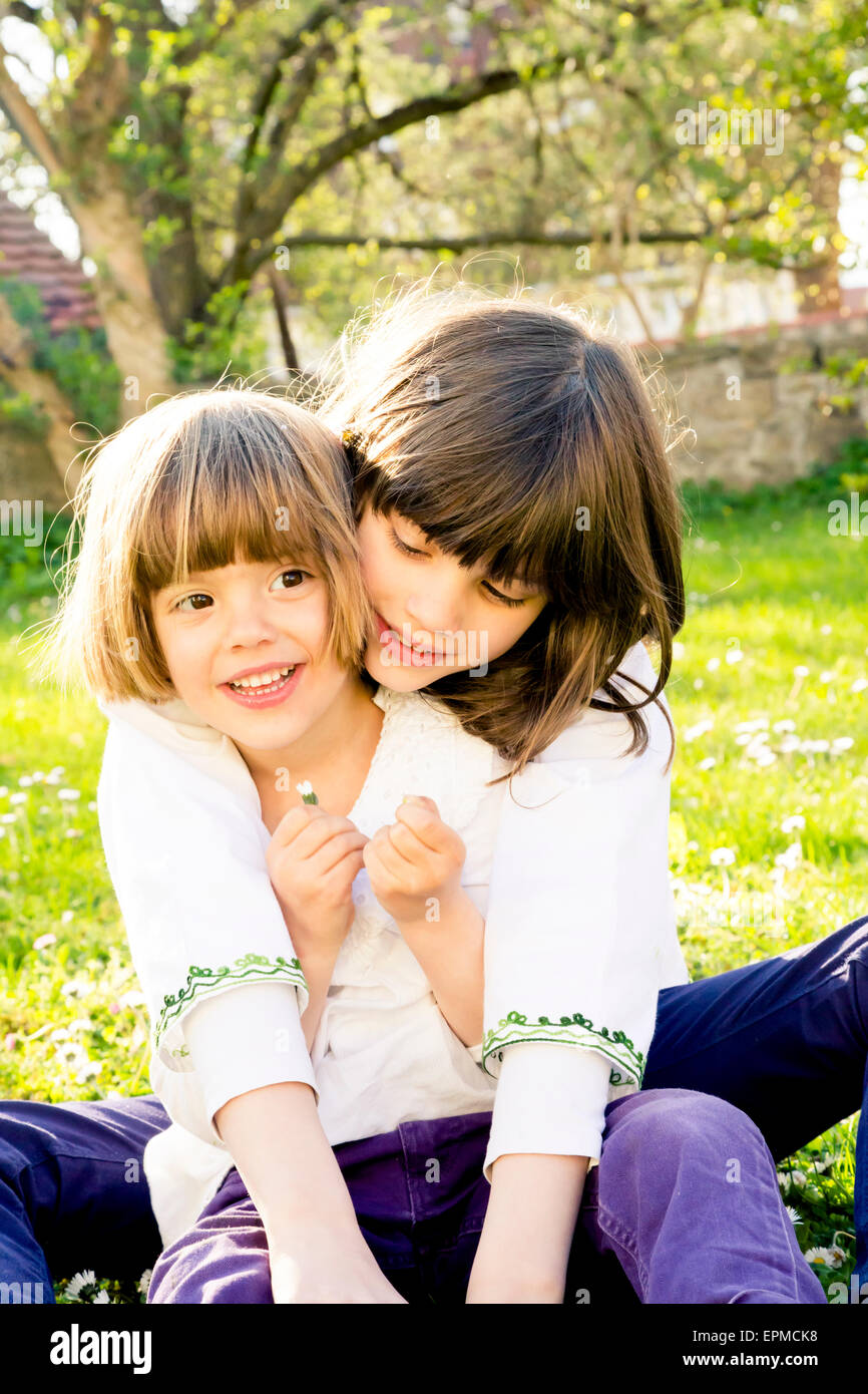 Two sisters sitting together on a meadow in the garden Stock Photo - Alamy