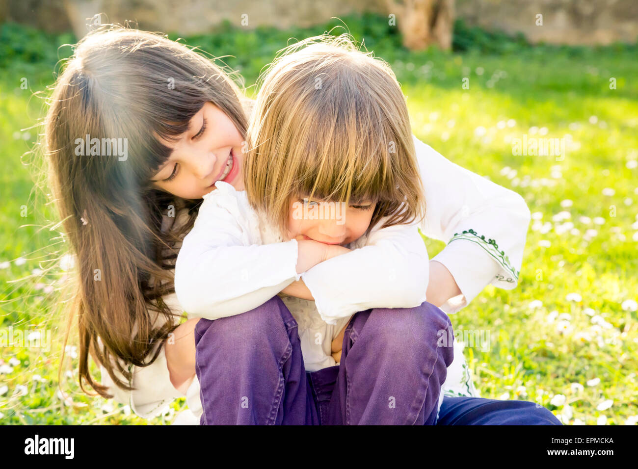 Two sisters sitting together on a meadow in the garden Stock Photo - Alamy