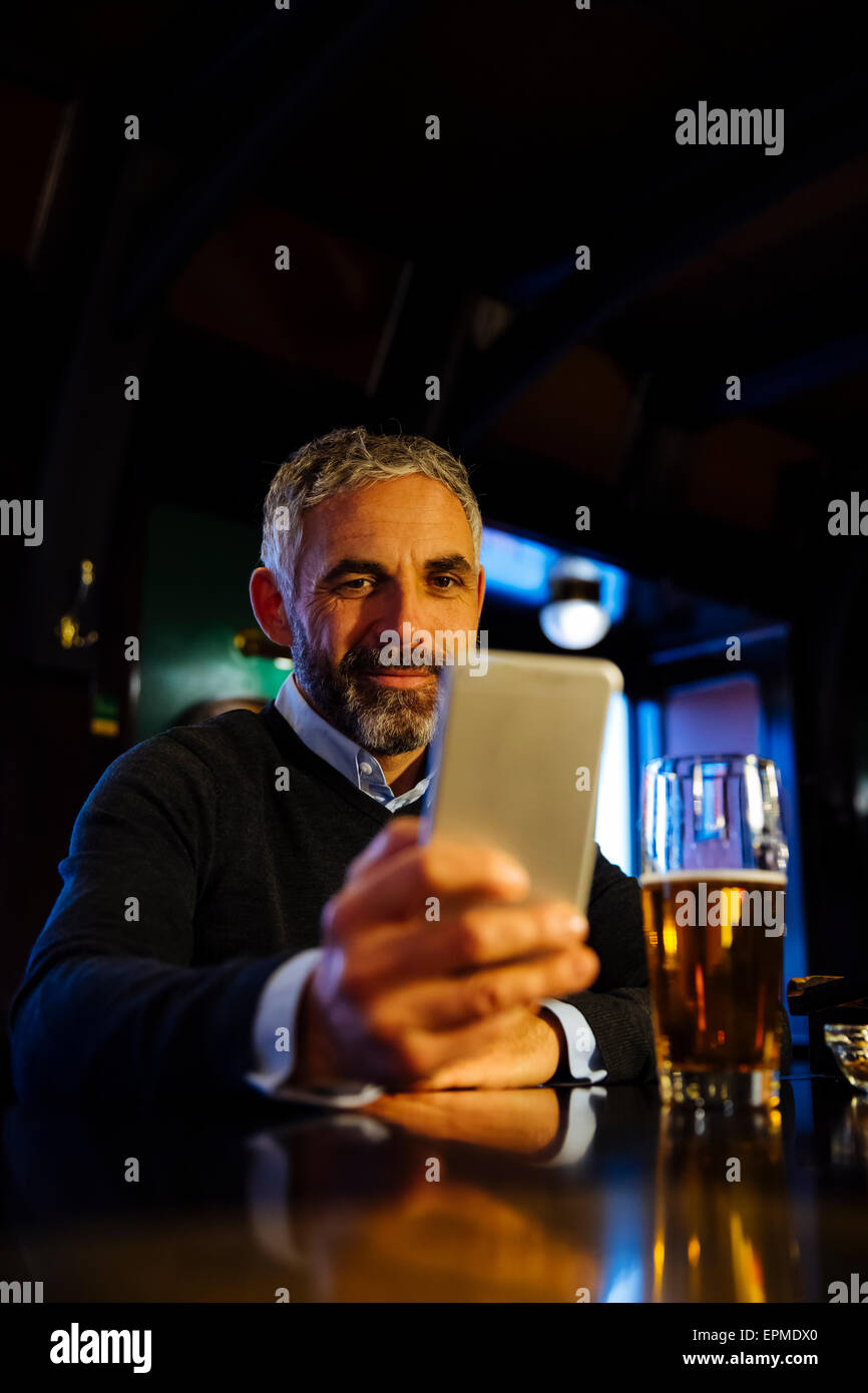 Man sitting at counter of a pub looking at his smartphone Stock Photo ...
