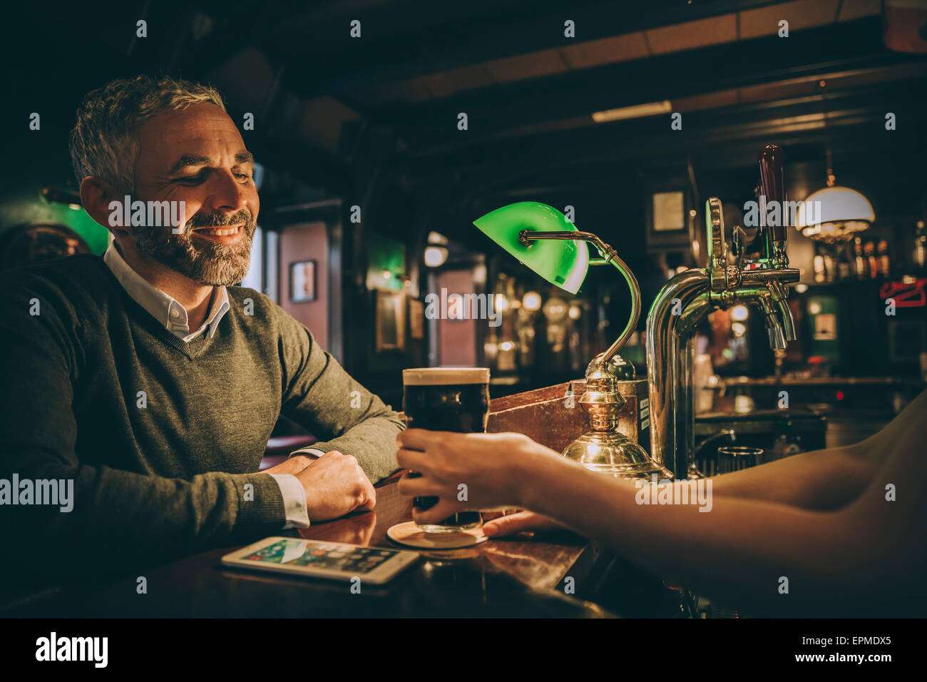 Smiling man sitting at counter of a pub Stock Photo - Alamy