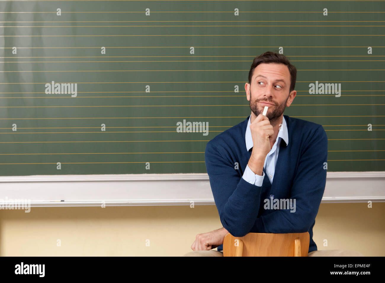 Teacher in classroom at blackboard thinking Stock Photo - Alamy