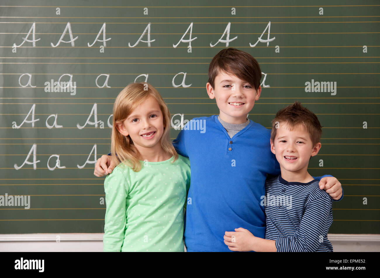 Three smiling pupils embracing at blackboard Stock Photo - Alamy