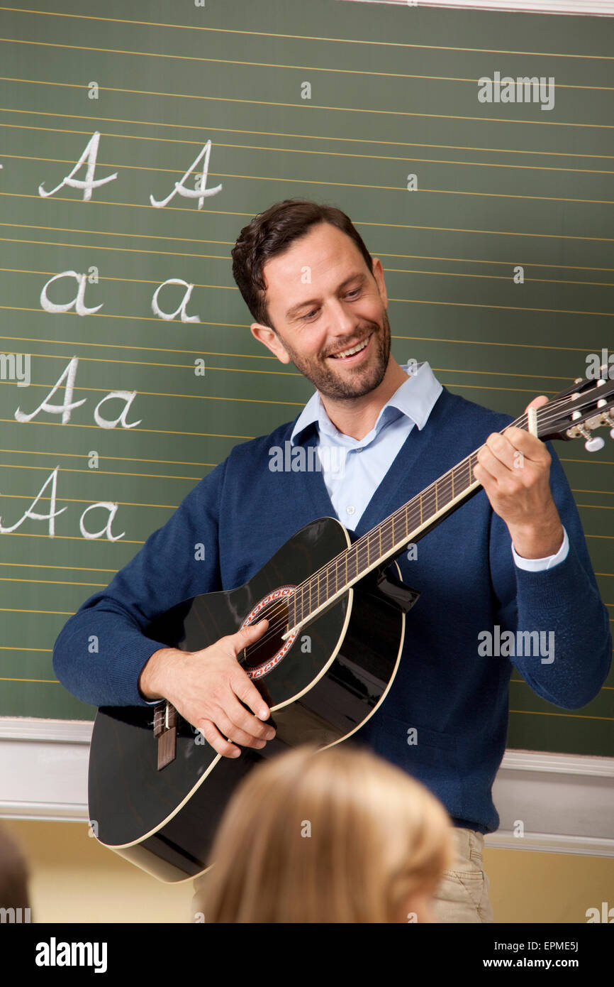 Teacher playing guitar in classroom Stock Photo - Alamy