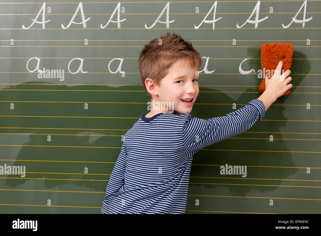 Schoolboy at blackboard wiping away letter A Stock Photo - Alamy