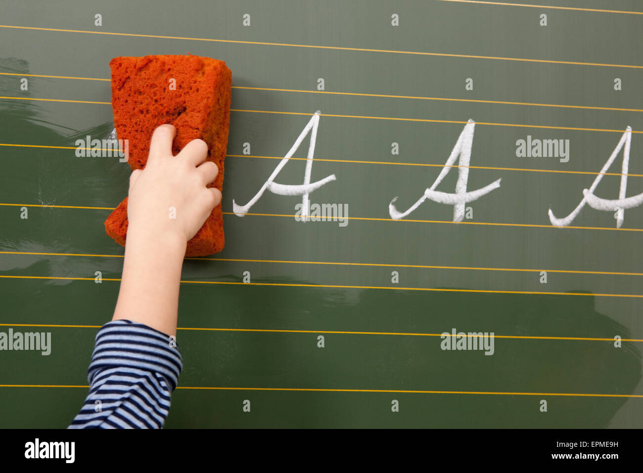 Schoolboy at blackboard wiping away letter A Stock Photo - Alamy