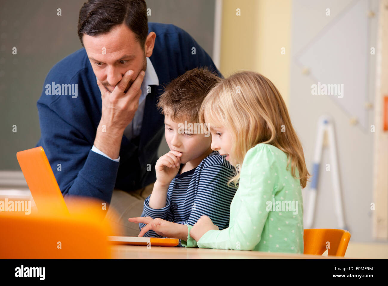 Teacher with pupils using laptop in classroom Stock Photo - Alamy
