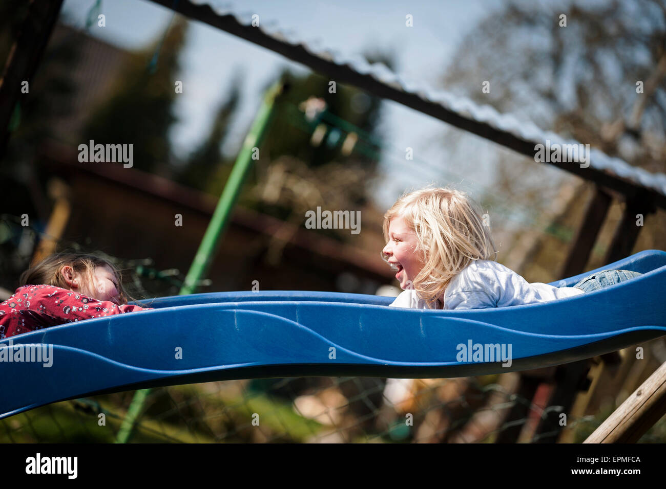Two happy girls on a slide Stock Photo - Alamy