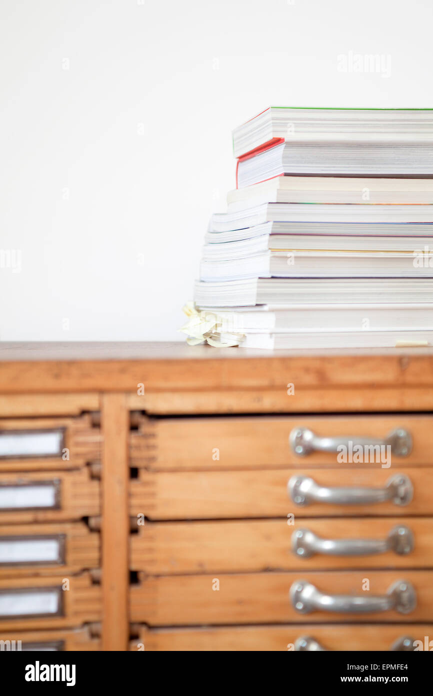 Stack of books and magazines on a wooden drawer cabinet Stock Photo - Alamy