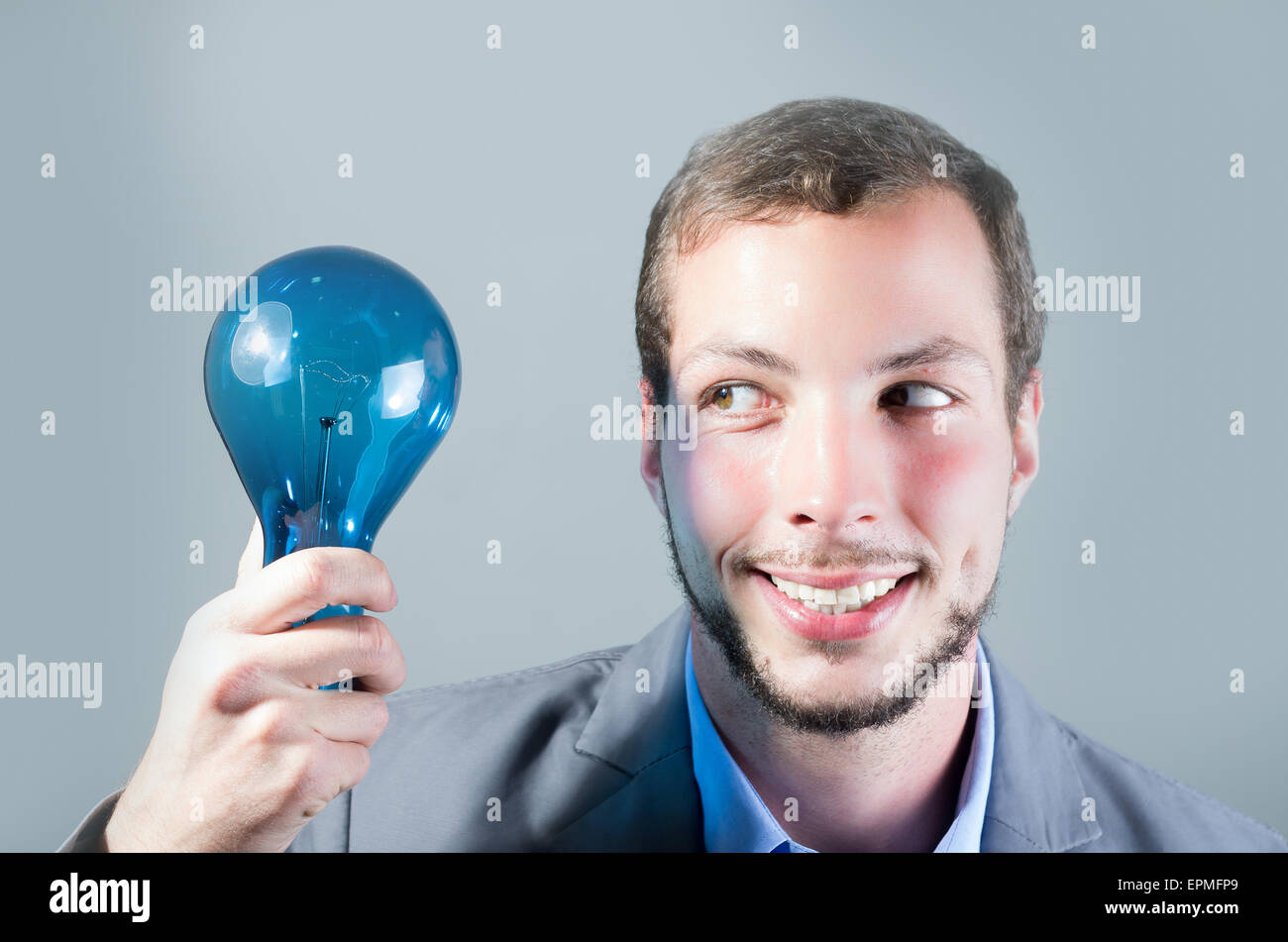 Handsome young smart man holding a blue light bulb Stock Photo - Alamy