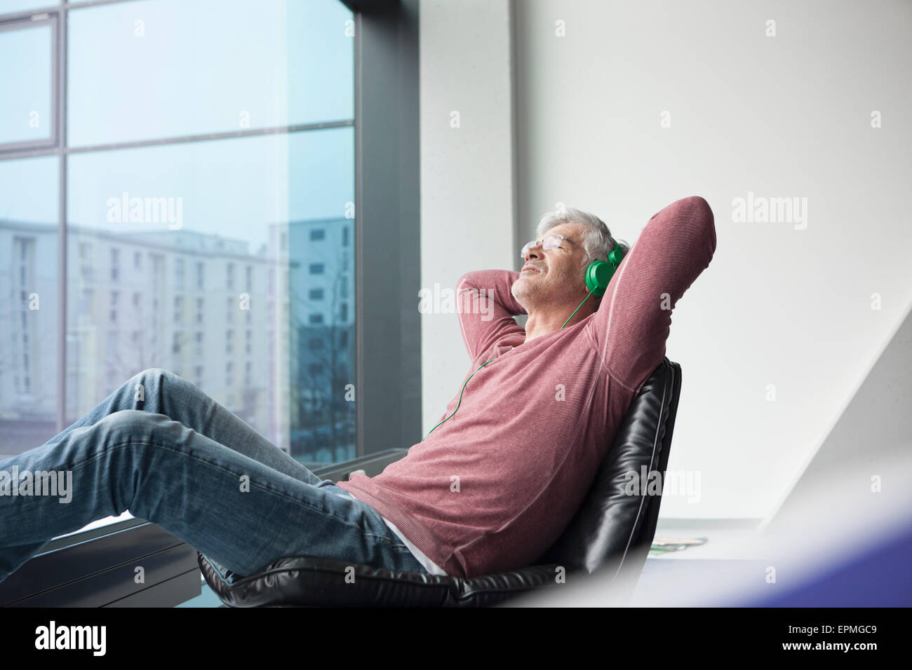 Man sitting in a leather chair hearing music with headphones Stock ...